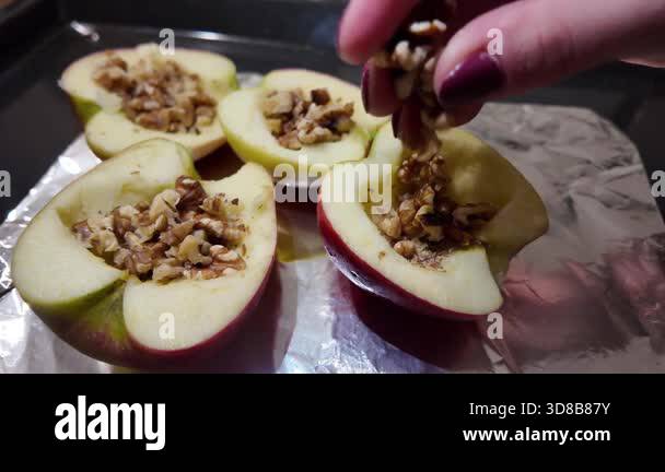 apple halves filled with chopped nuts, foil-lined tray, close-up of ...