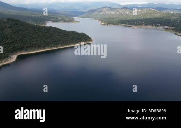 High-angle drone footage flying over a vast mountain lake surrounded by ...