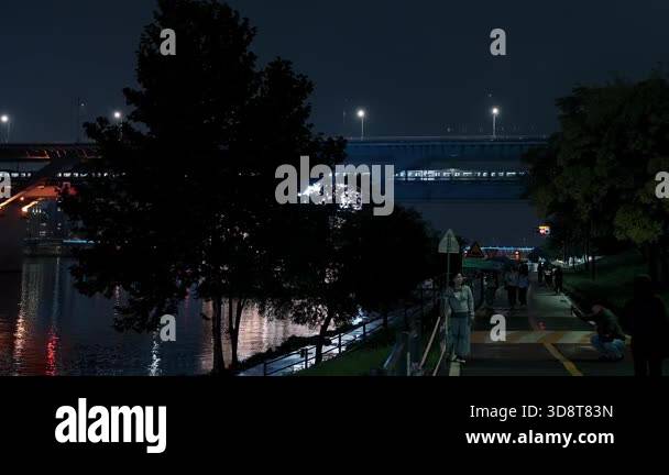 SEOUL, SOUTH KOREA - OCTOBER 11, 2025 - People enjoying a night stroll along the riverbank with ...