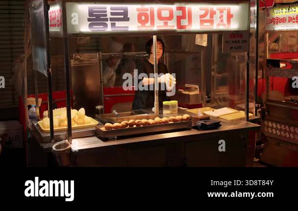 BUSAN, SOUTH KOREA - OCTOBER 10, 2025 - Vendor preparing potato snacks ...