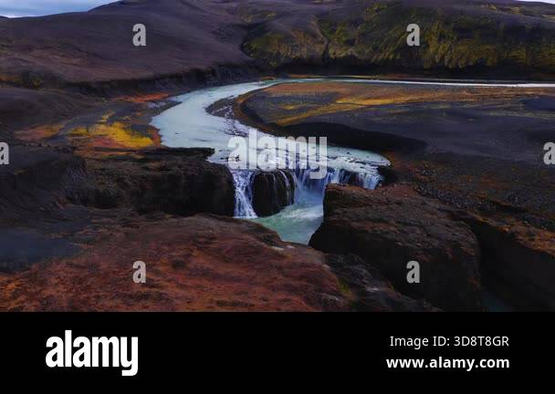 Aerial view shows pale turquoise river curving over black sand into a ...