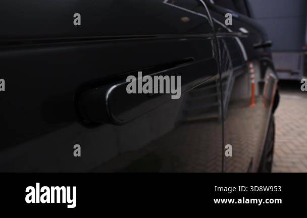 Low angle close up shows glossy pop out handle with button on black SUV ...