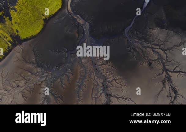 Top down aerial view shows braided milky blue meltwater over charcoal ...