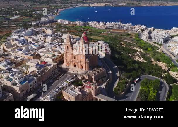Aerial shot shows Mellieha parish basilica, winding roads, limestone ...