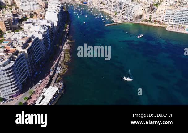 High aerial of Sliema, Malta, shows crescent bay with moored boats, a ...