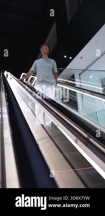 A man rides an upward escalator in a glass walled multi level Tokyo ...