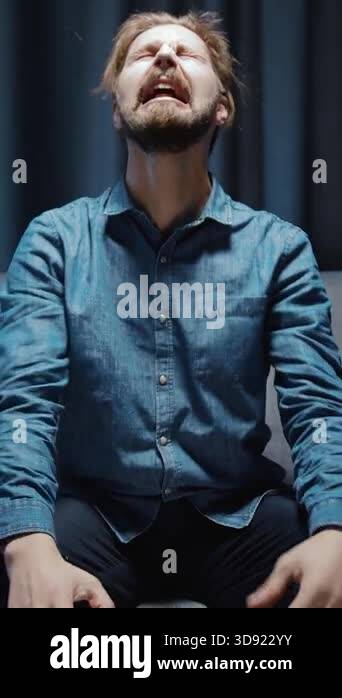 A person expresses intense emotions while sitting at home during a ...