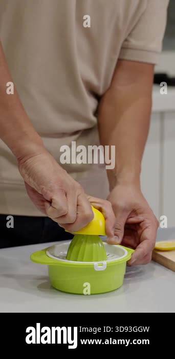Close-up of hands pressing lemon half on manual citrus juicer. Vertical ...