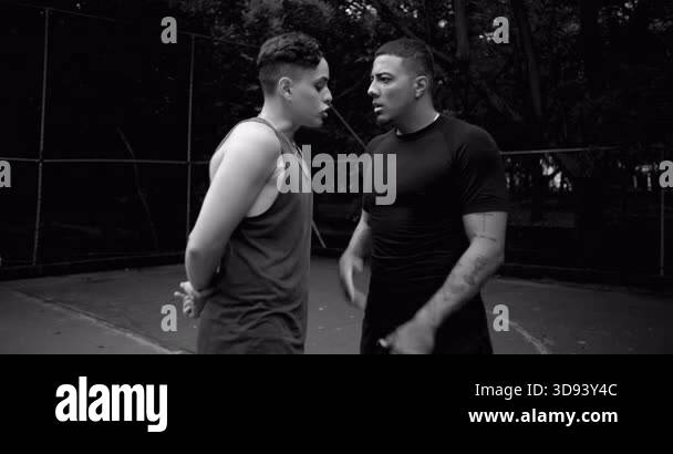 Two Hispanic men arguing face to face on basketball court, in black and ...