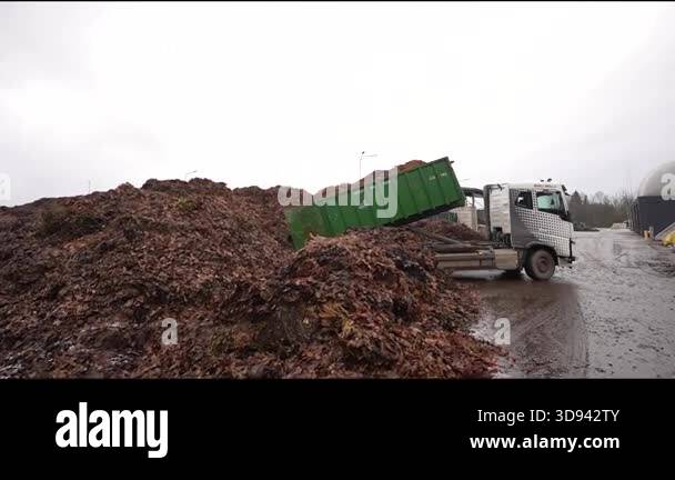 Cesis, Latvia - November 21, 2025: Truck is unloading green container ...