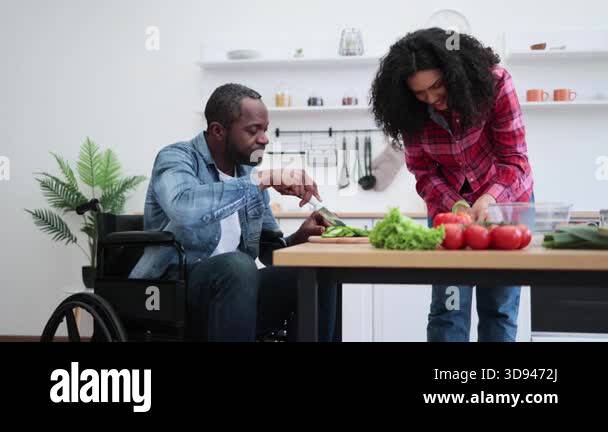 A couple is preparing a meal together in a bright, modern kitchen. One ...