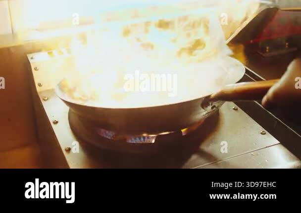 Cinematic shot of a professional chef cooking asian food in a wok pan ...