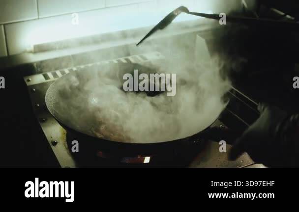 Cinematic shot of a professional chef cooking asian food in a wok pan ...