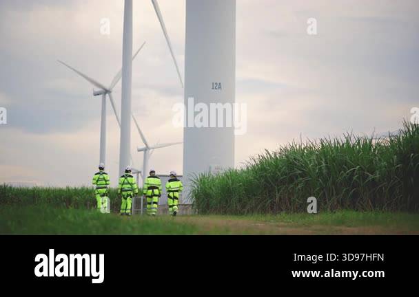 Team of engineers wearing safety helmets inspecting wind turbines at a ...