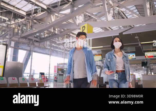 Man and woman passengers wearing face mask walking in airport terminal ...
