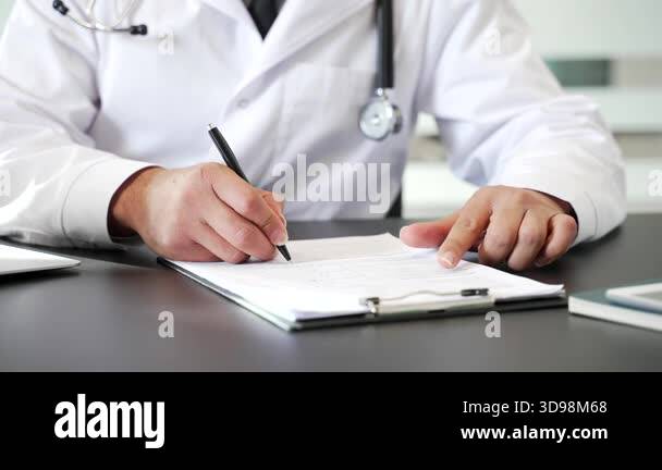 Close up of doctor's hand signing medical documents in hospital office ...