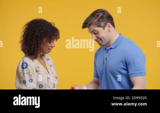 Young american couple on yellow studio background. White man gives gift ...