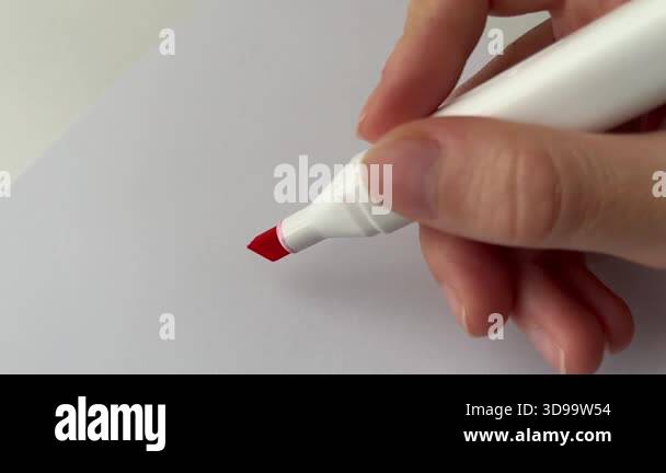 A hand draws a straight line on white paper with a red marker pen Stock ...