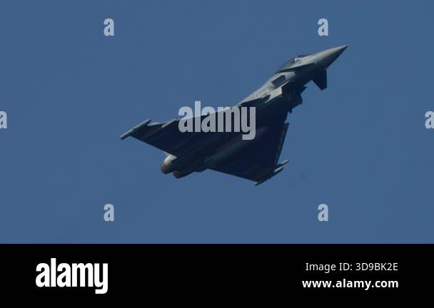 Military fighter jet performs steep banking turn against clear blue sky ...