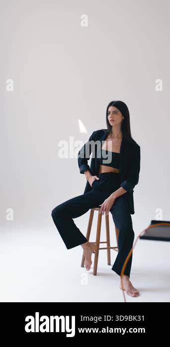 Professional photographer taking photos of a model sitting on a stool ...
