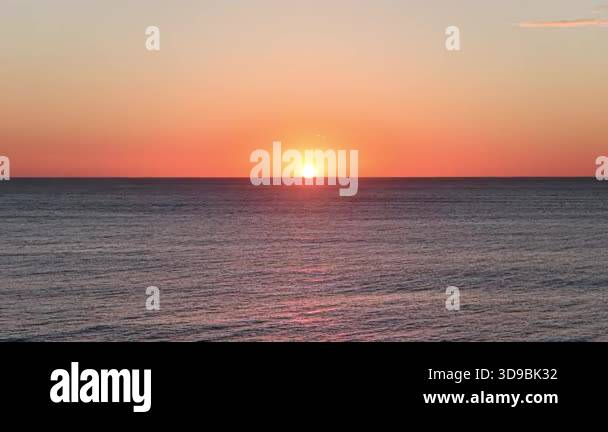 Majestic sun dipping below the tranquil ocean horizon at sunset. The ...