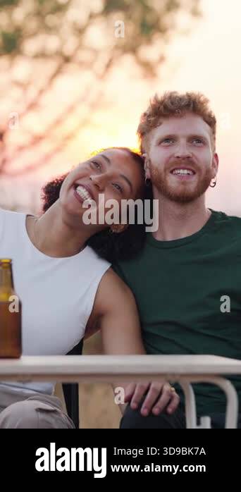 Happy multiracial young couple sitting at an outdoor cafe, enjoying a ...