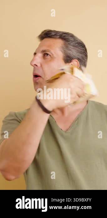 Middle-aged man with graying hair smelling and fanning his face with a ...