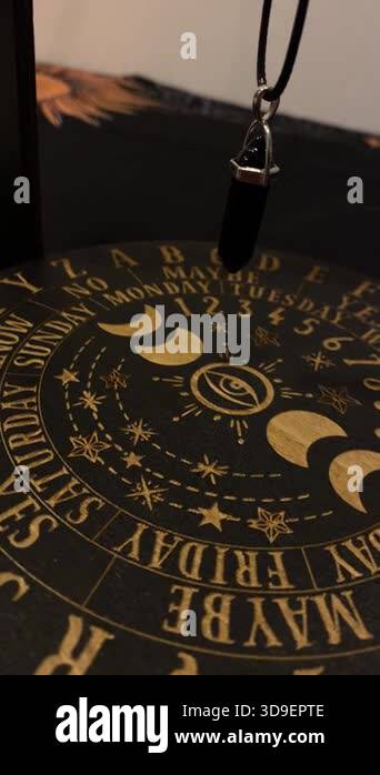 Pendulum over a spirit board on a wooden table with candles esoteric ...