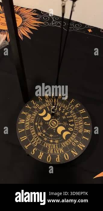 Pendulum over a spirit board on a wooden table with candles esoteric ...