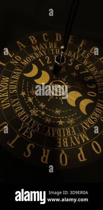 Pendulum over a spirit board on a wooden table with candles esoteric ...