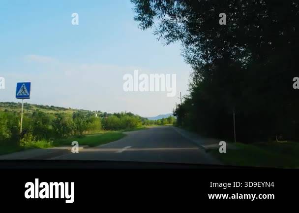 Panorama shows blue sky over low hills while road edge slides past ...