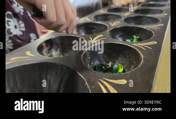 The traditional Malay board game, Congkak. Glass marbles are used as ...
