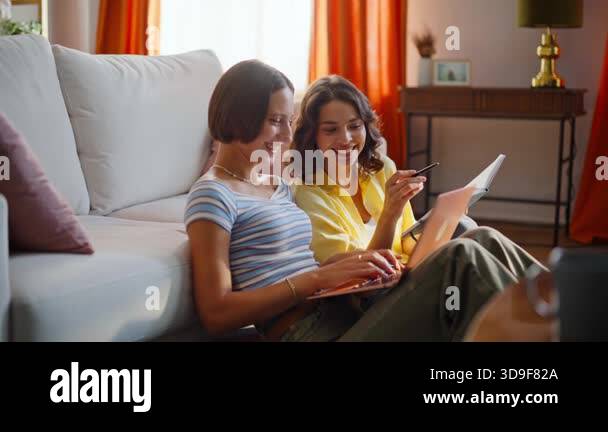 Enthusiastic girls creating startup at home sitting floor near cozy ...