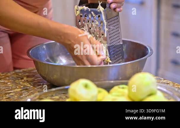 Closeup view of grating fresh apples on a hand grater. Simple food ...
