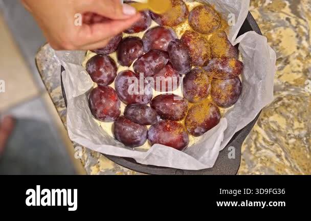 Woman preparing a pie at home, sprinkling cinnamon and sugar from above ...