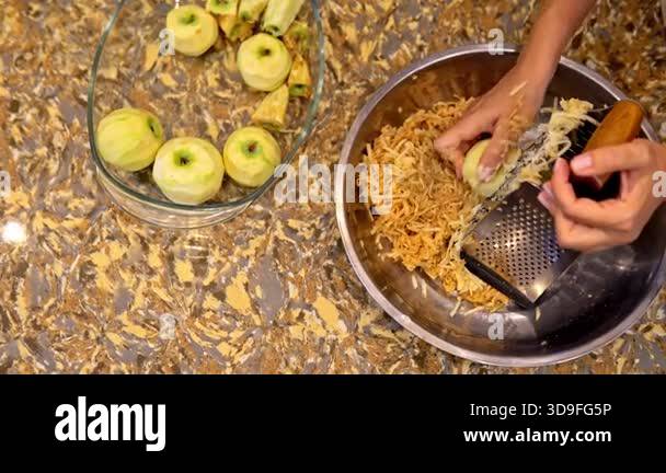 Closeup view of grating fresh apples on a hand grater. Simple food ...