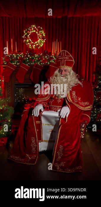 Saint Nicholas in fancy red and gold clothes sits by a festive ...