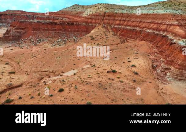 Rocks of curved shape and visible layers. Scarce green shrubs grow in ...