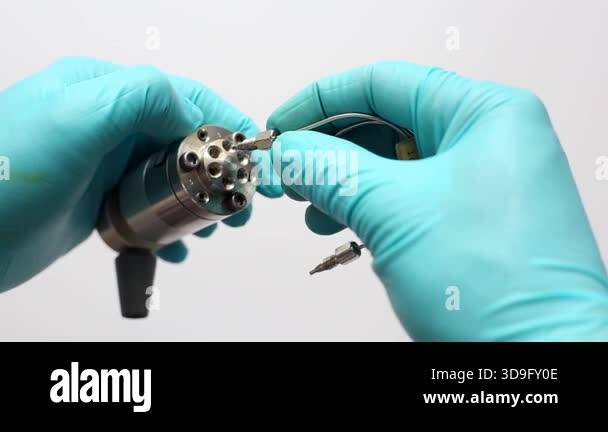 A scientist in blue gloves installs a 100 L sample loop onto a manual ...