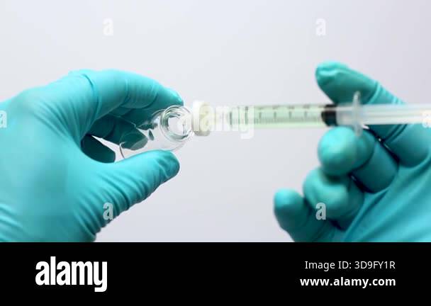 A scientist's hand grips a glass autosampler vial as a liquid sample is ...