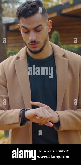 Worried Hispanic man guy in autumn park look around waiting for meeting ...
