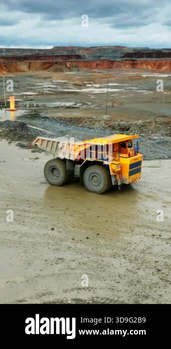 two yellow dump trucks crossing muddy haul road, high clearance wheels ...
