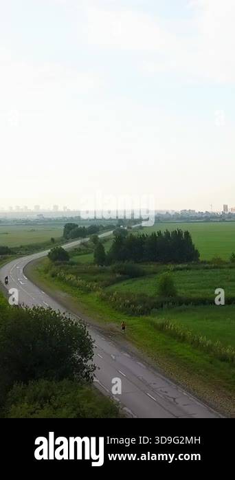 Aerial footage of a biker riding a motorcycle on a scenic country road ...