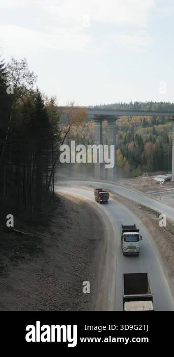 Aerial view of several dump trucks driving on a dusty road near a ...