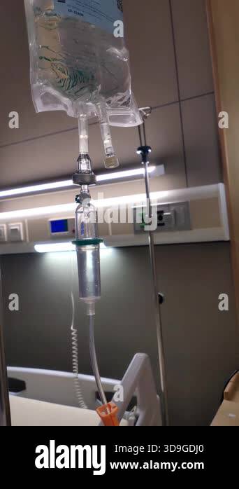 A close-up shot of an intravenous (IV) fluid bag and drip chamber ...