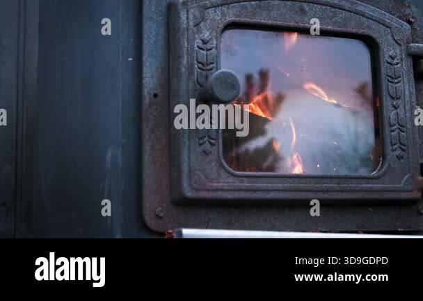 Bright orange flames consume wood logs inside a vintage cast iron stove ...
