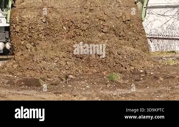 A construction vehicle unloads a large amount of soil at a worksite ...
