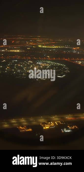 city approach and runway lights seen from airplane window at night, co ...