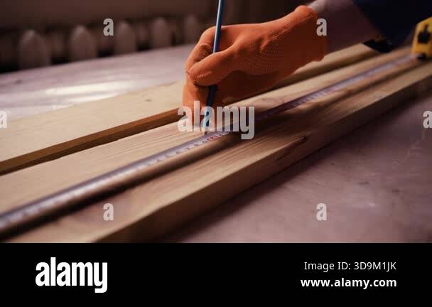 Carpenter marking with pencil and measure tape on wooden board ...