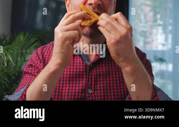 Caucasian man holding, biting and chewing fried chicken strip and ...